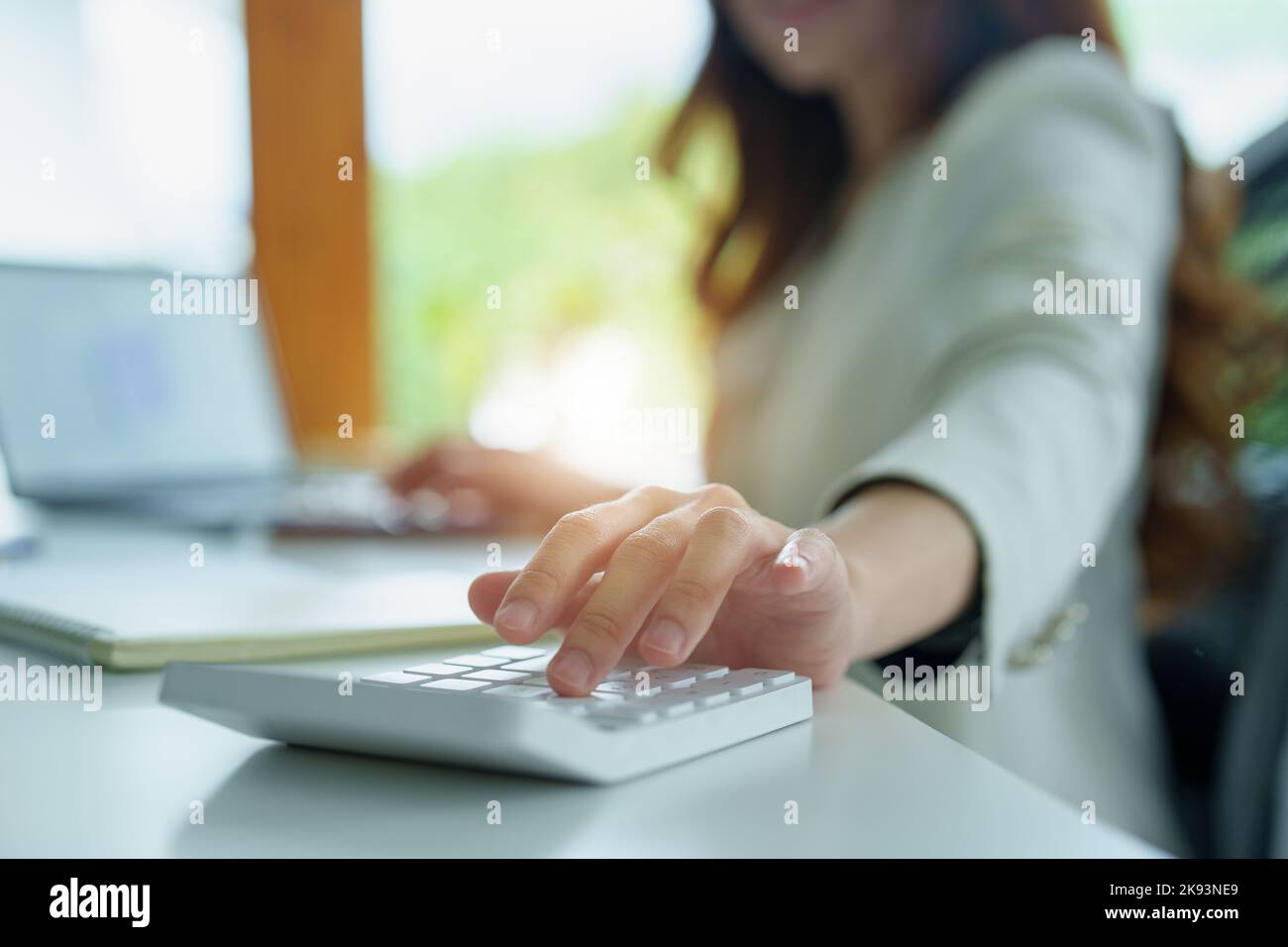Portrait of an Asian bank employee using a financial budget calculator ...