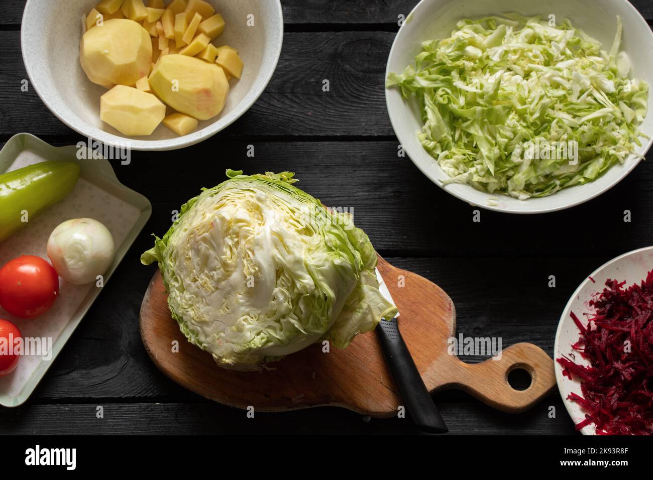cabbage potatoes pepper tomato beetle are slicing on the table, cooking ...