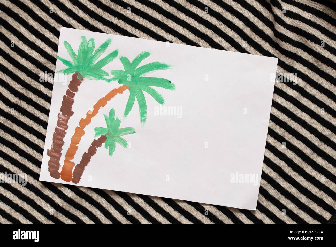three palm trees are drawn with paints on white paper on a striped ...