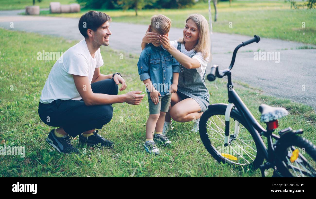 Loving parents are making surprise for little son closing his eyes and ...