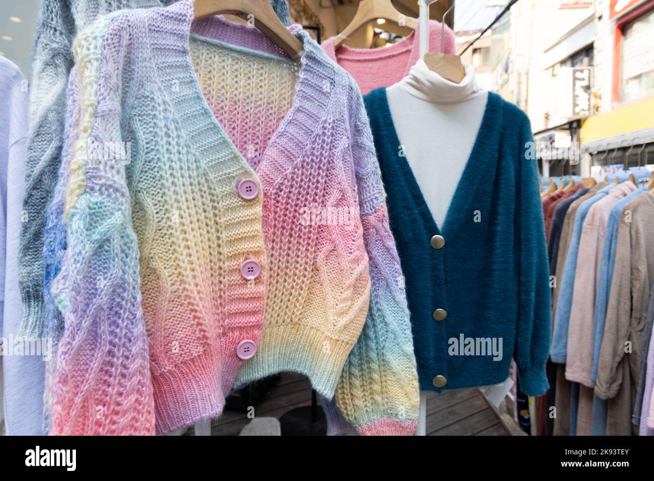 A shopping rank filled with clothes, colorful knited sweters. Bunch of ...