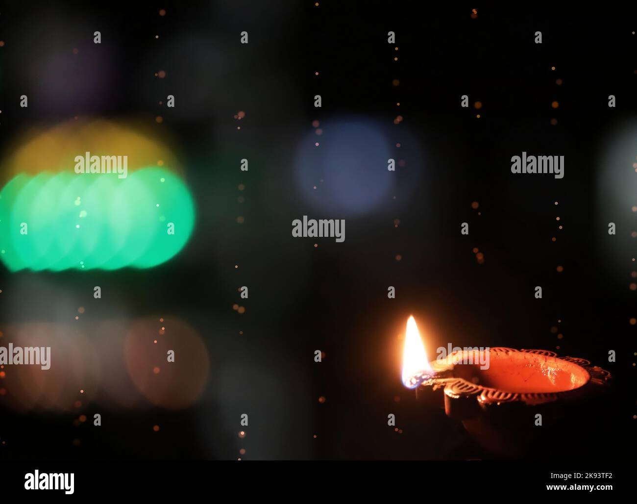 A single lit clay Diya against colorful bokeh background/Copy Space ...