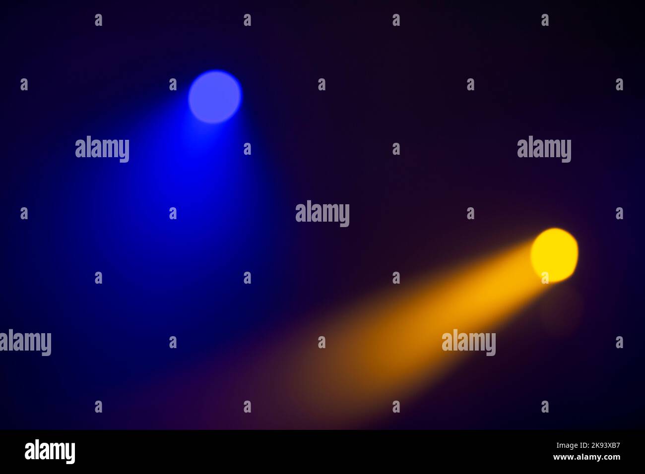 Orange beams of light from stage spotlights on a dark blue background ...