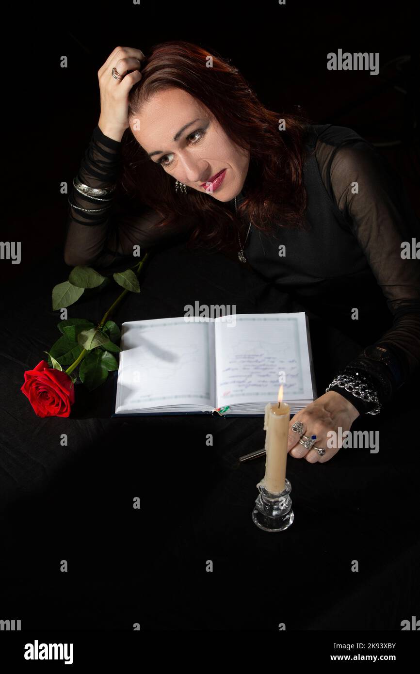 Sad middle aged woman with rose notepad and candle. Write poetry, a ...