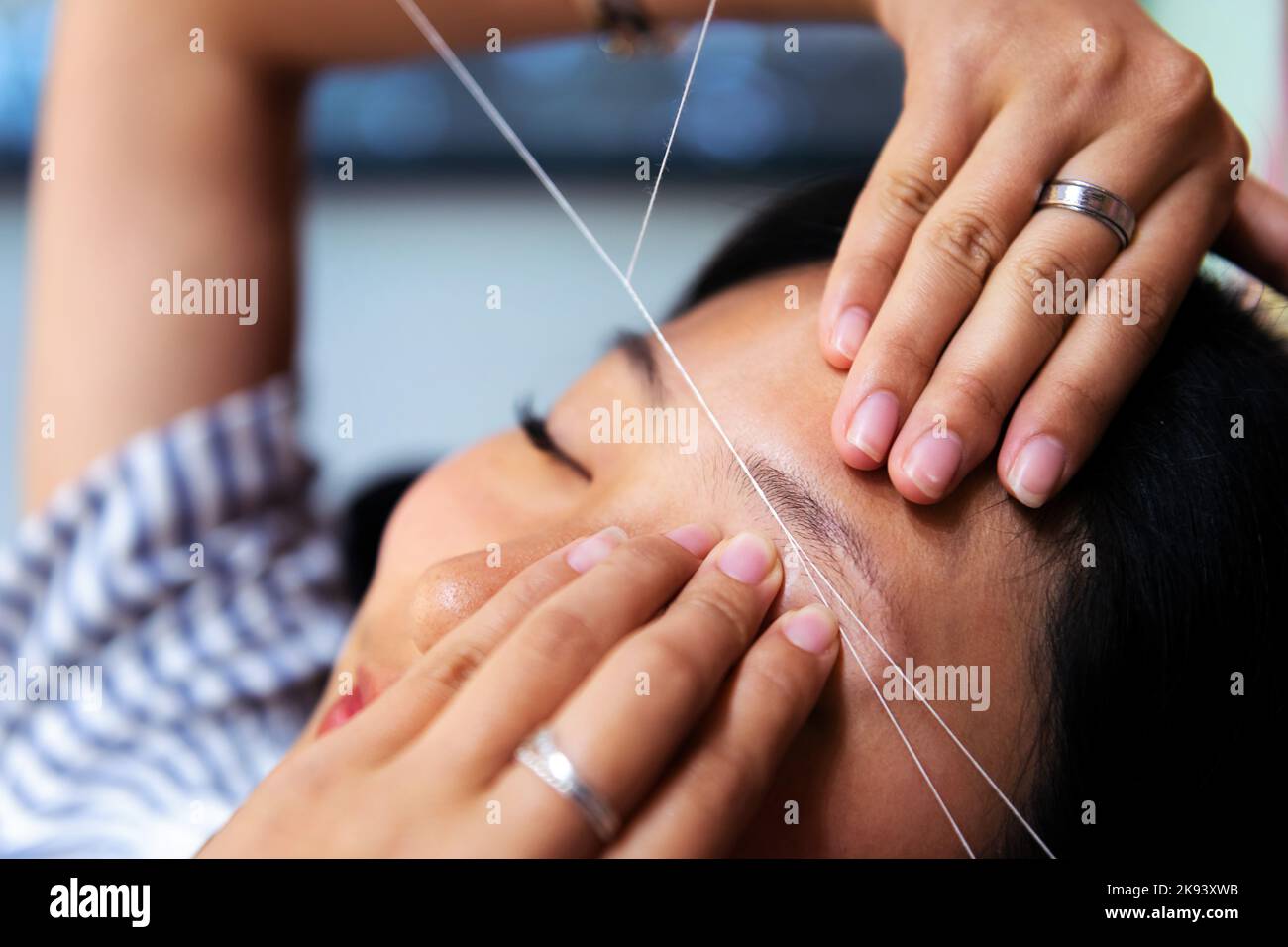 eyebrow waxing with threading on a young woman Stock Photo - Alamy