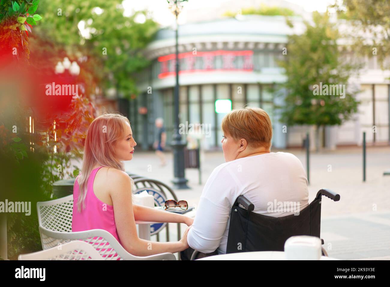 Woman with disability sitting in a wheelchair in outdoor cafe with her ...