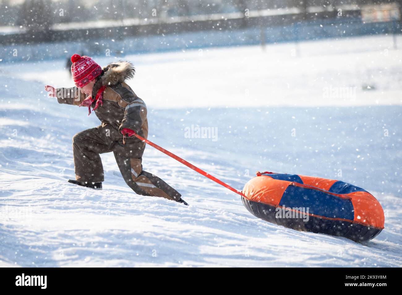 A happy boy up in the air on a tube sledding in the snow.. A boy slides ...