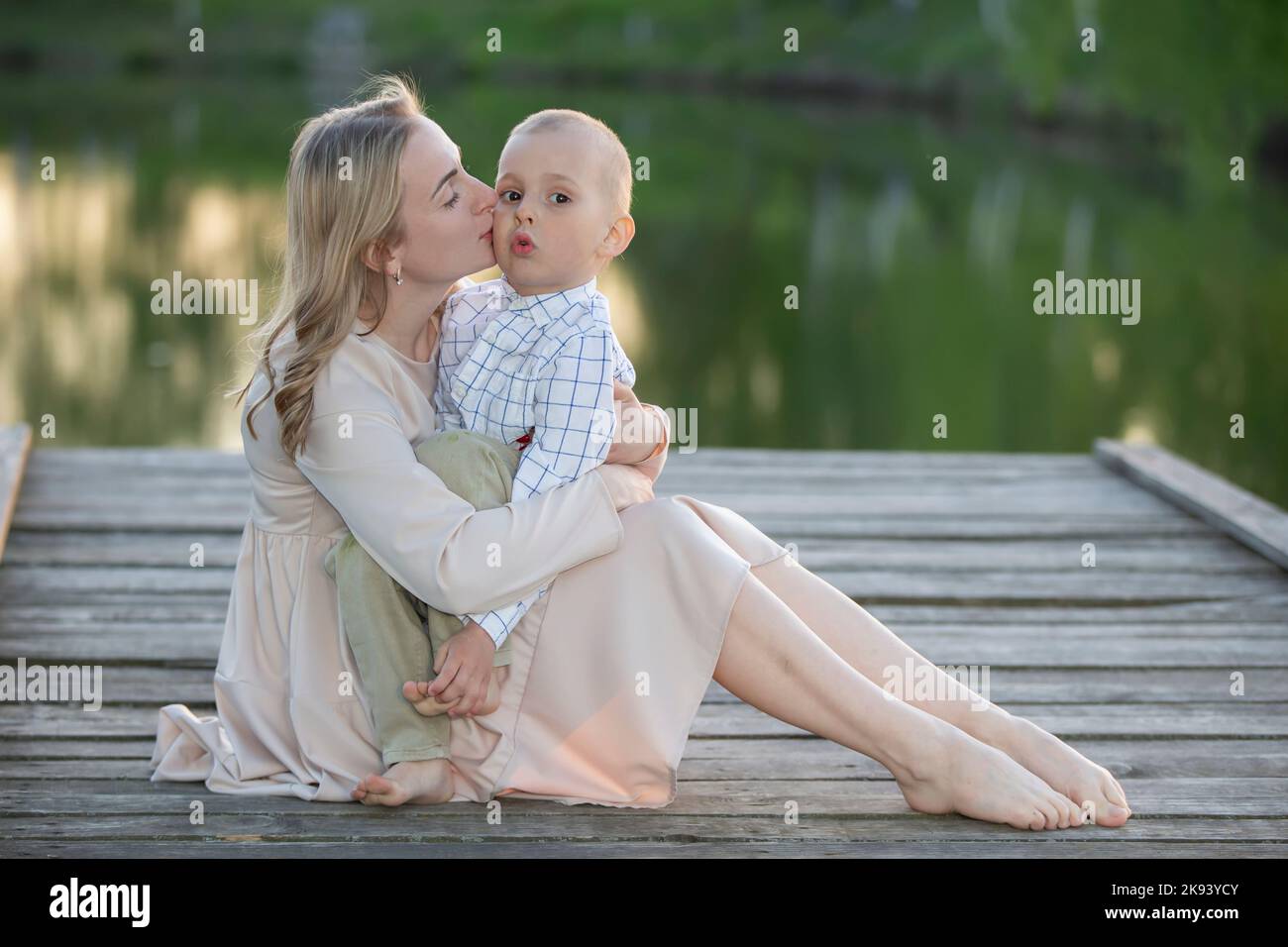 Mom gently kisses her little son against the backdrop of nature ...