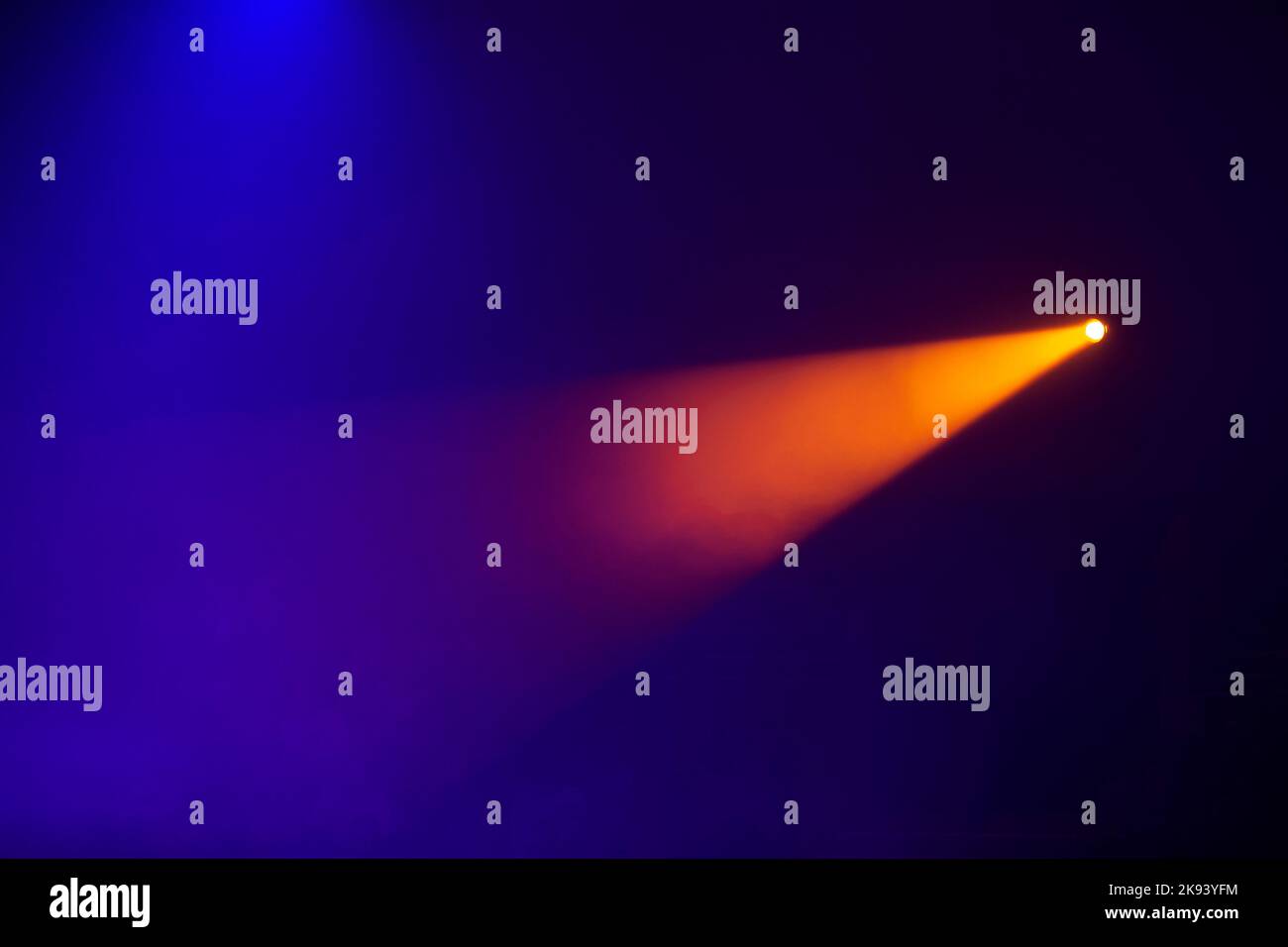 Orange beams of light from stage spotlights on a dark blue background ...