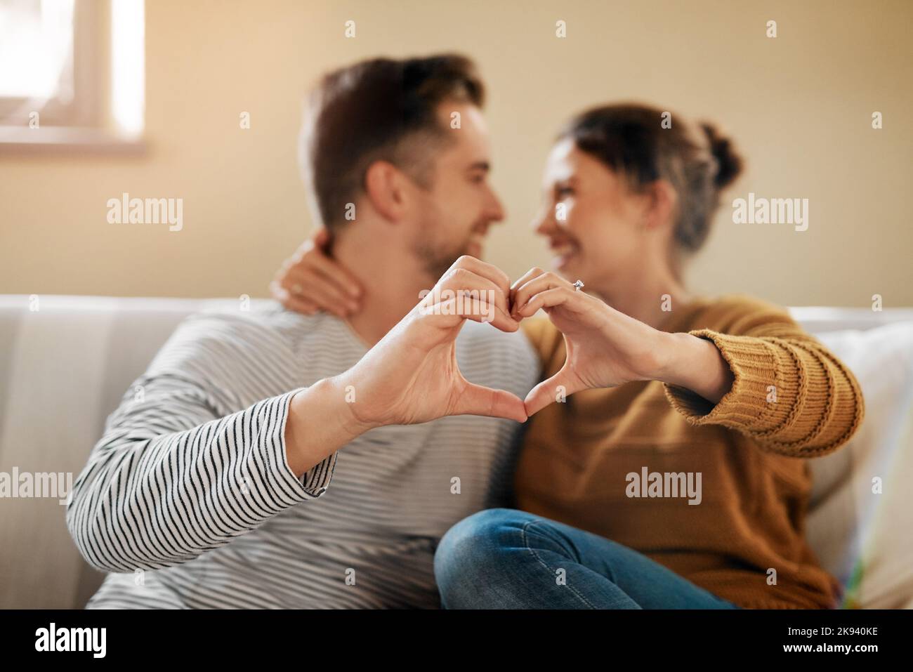 Love lives here. a couple forming a heart shape with their hands while ...