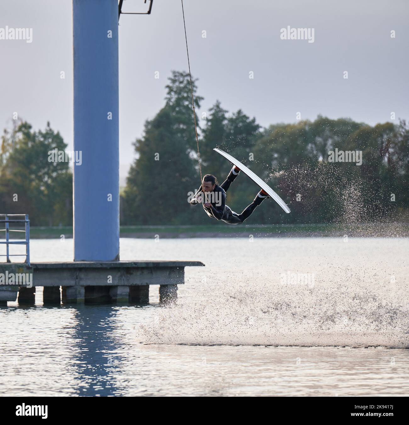 Wakeboarder making tricks while wakeboarding on lake. Young man surfer ...