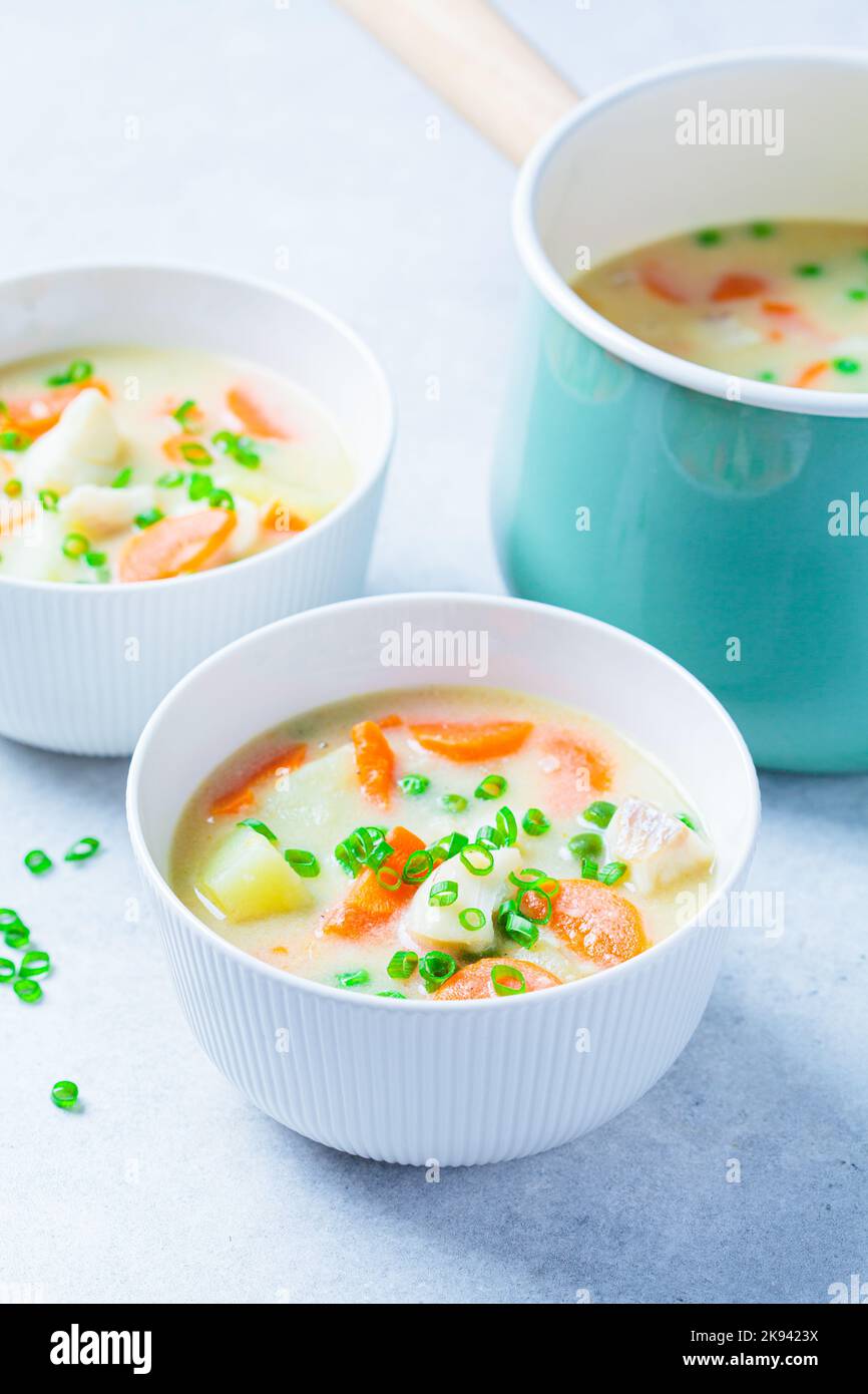 Fish cod chowder soup with green peas, potatoes and carrots in a white ...