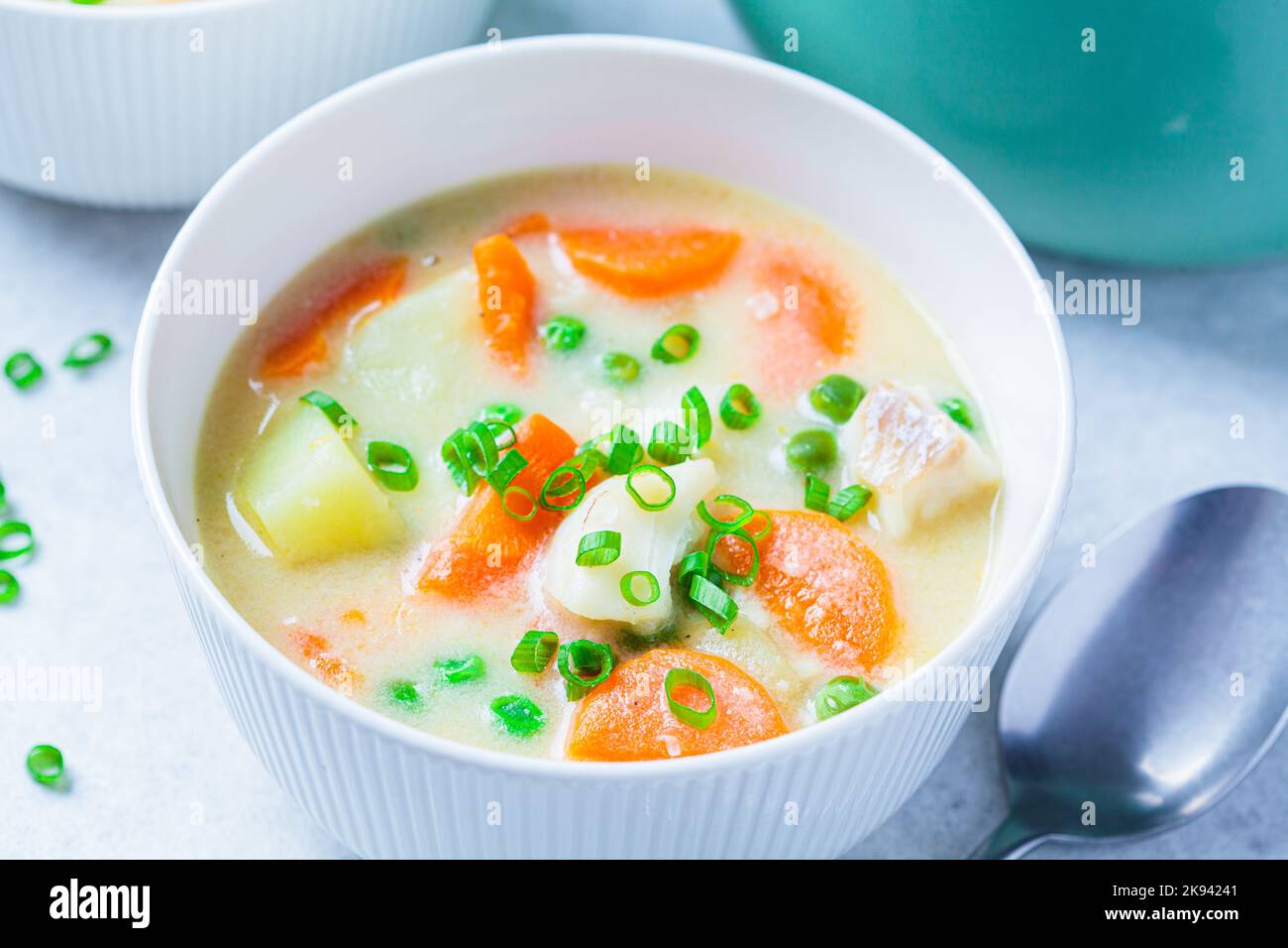 Fish cod chowder soup with green peas, potatoes and carrots in a white ...