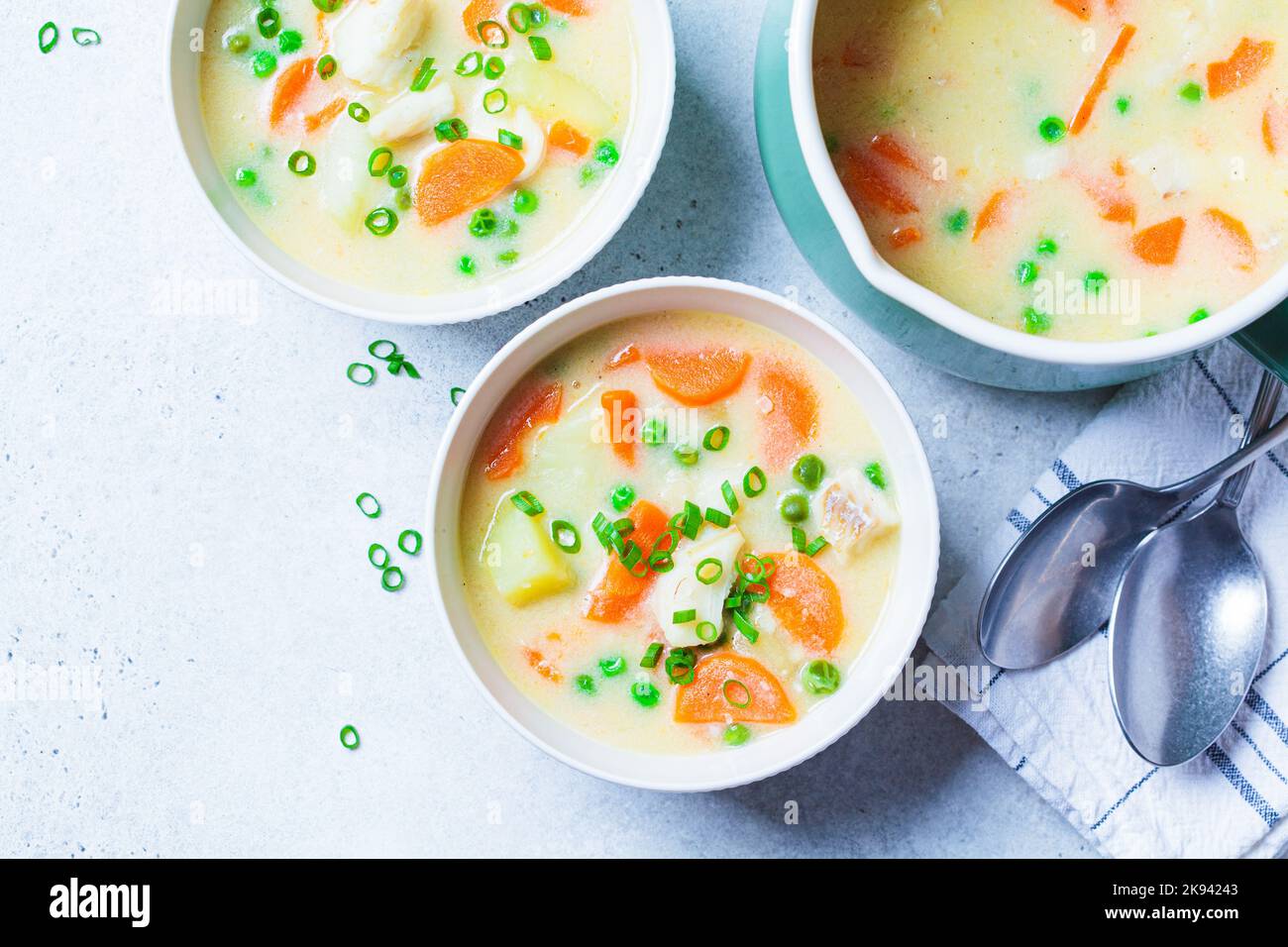 Fish cod chowder soup with green peas, potatoes and carrots in a white ...