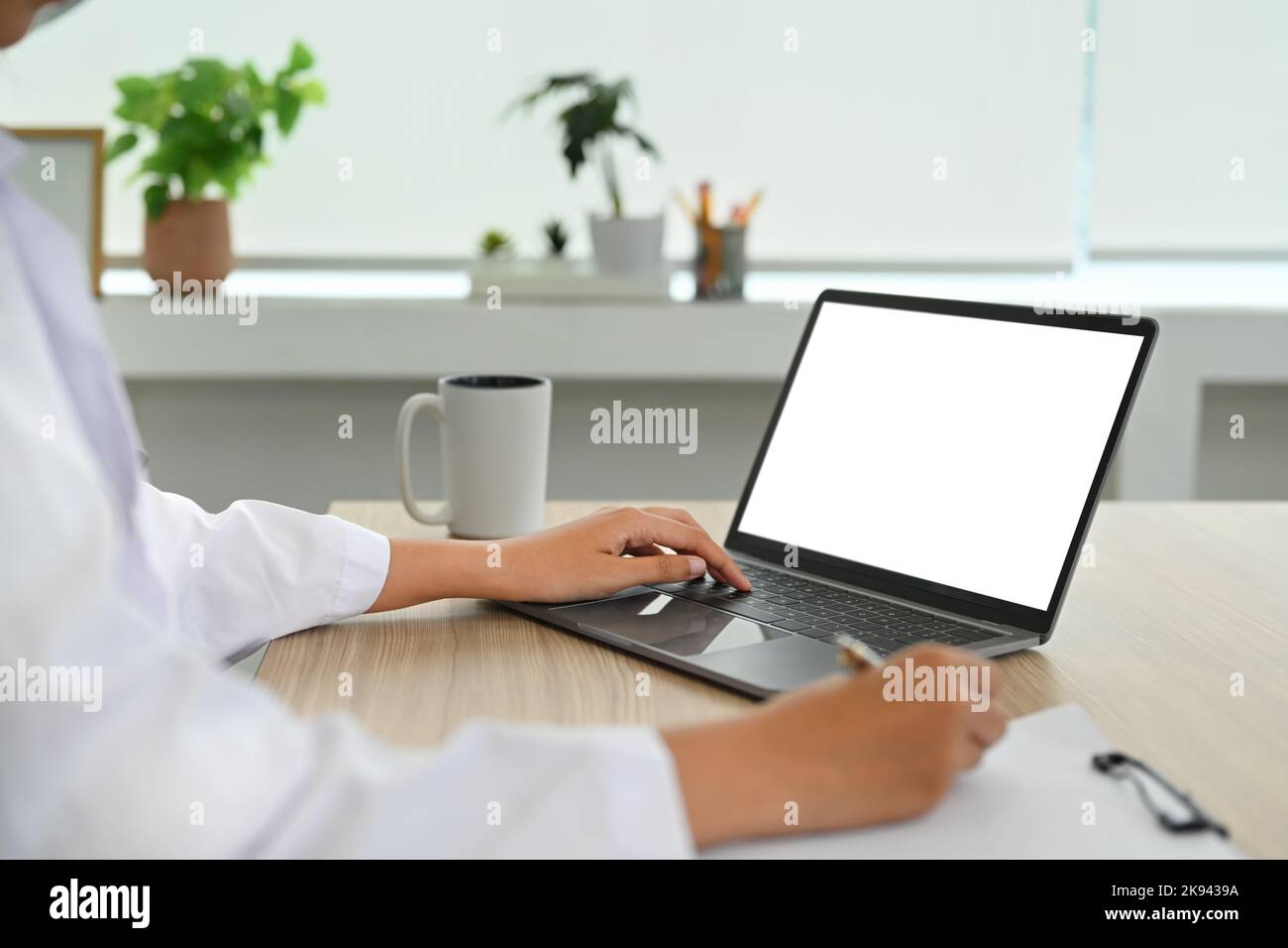 Close up view of doctor using laptop and taking notes in medical ...