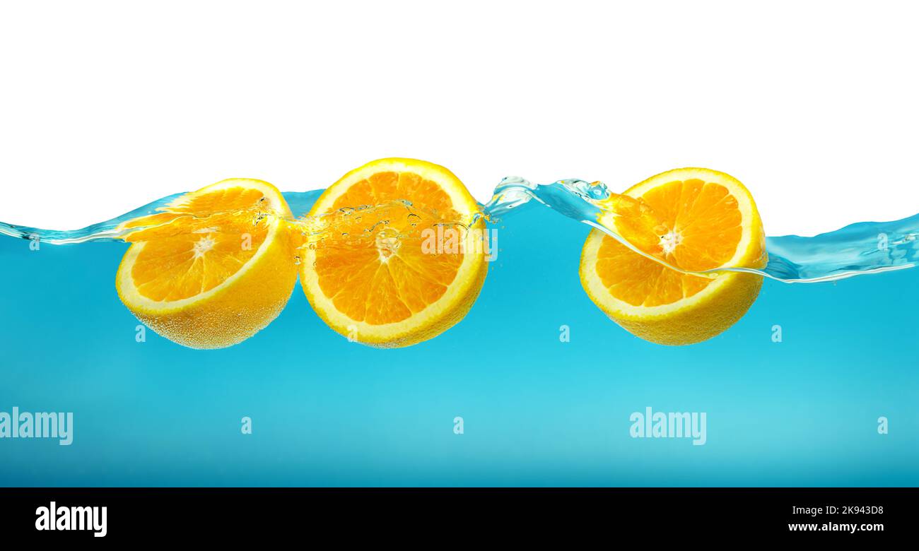 Fresh orange fruits flowing in blue water wave with splash isolated on ...