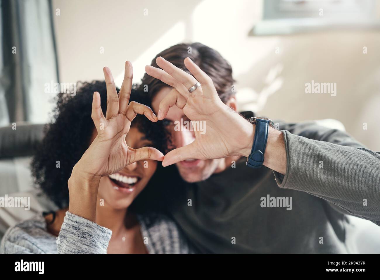 Our hearts are one and the same. a playful young couple making heart ...