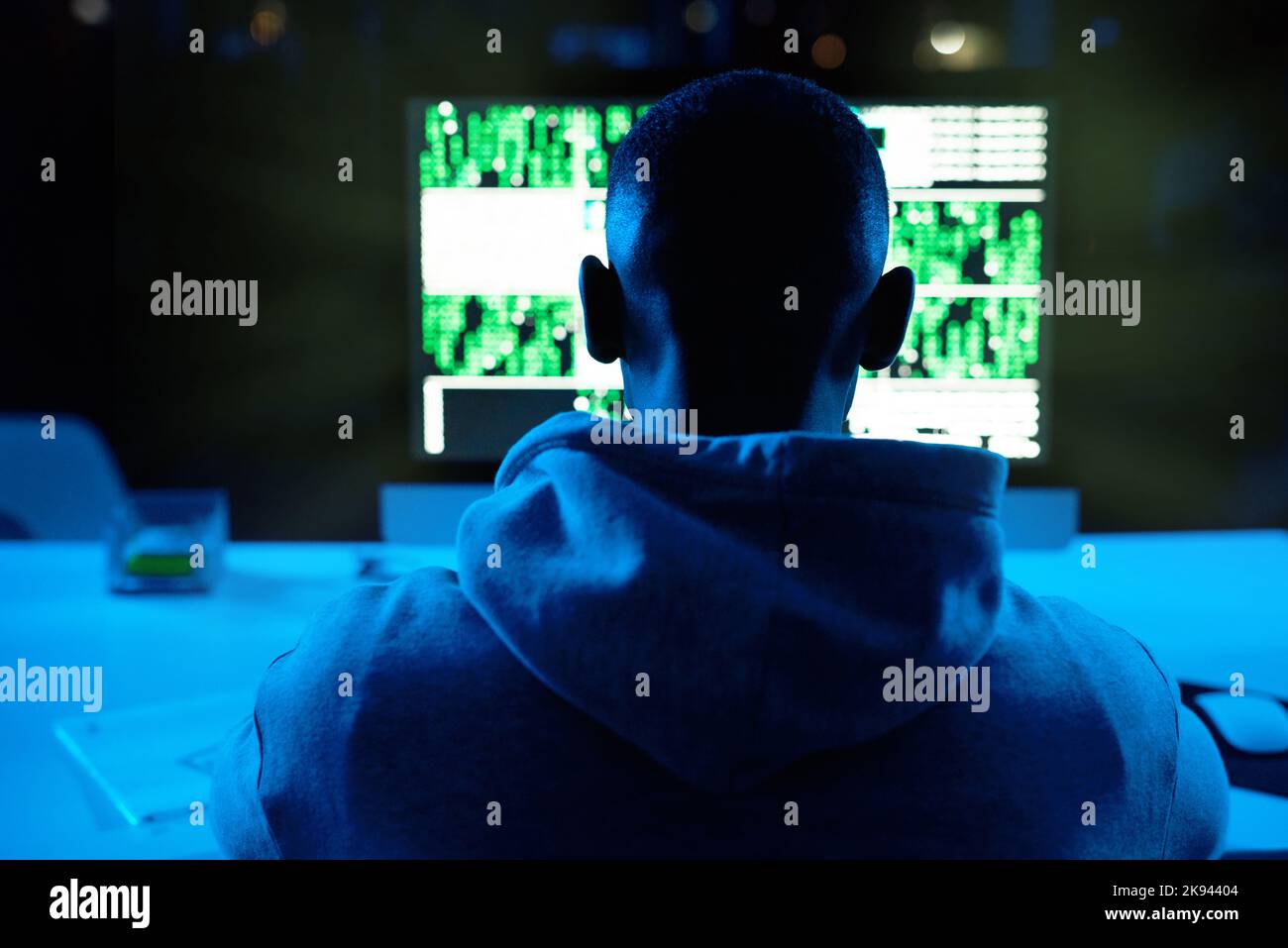 Hes back to his old ways again. Rearview shot of a male hacker cracking a computer code in the ...