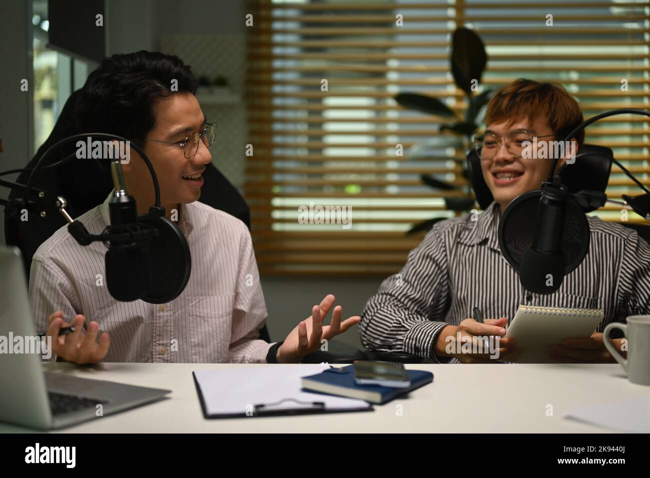 Happy male radio hosts using condenser microphone, recording voice over ...