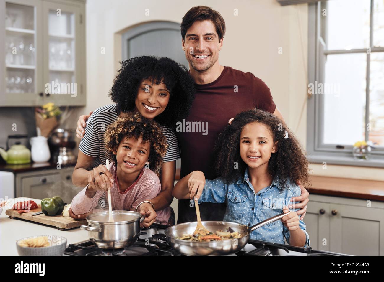 Dinner will be ready in a bit. a family of four cooking together in ...