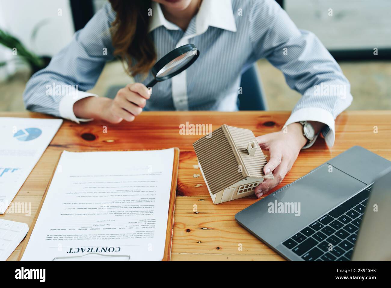 customer holding a magnifying glass to look at a house model inspection Stock Photo - Alamy