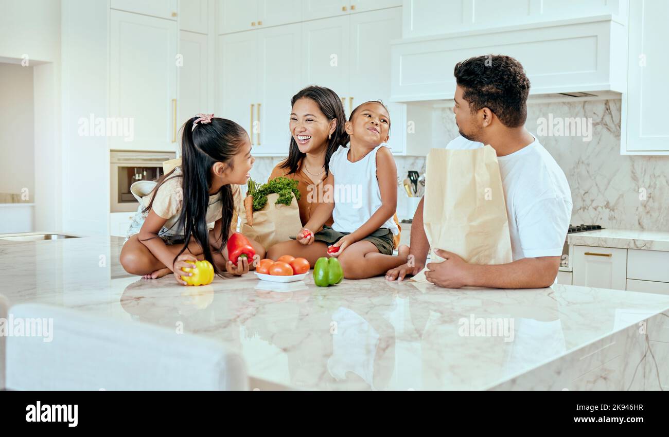 Asian, family and vegetables in kitchen for laugh at table, happy or ...