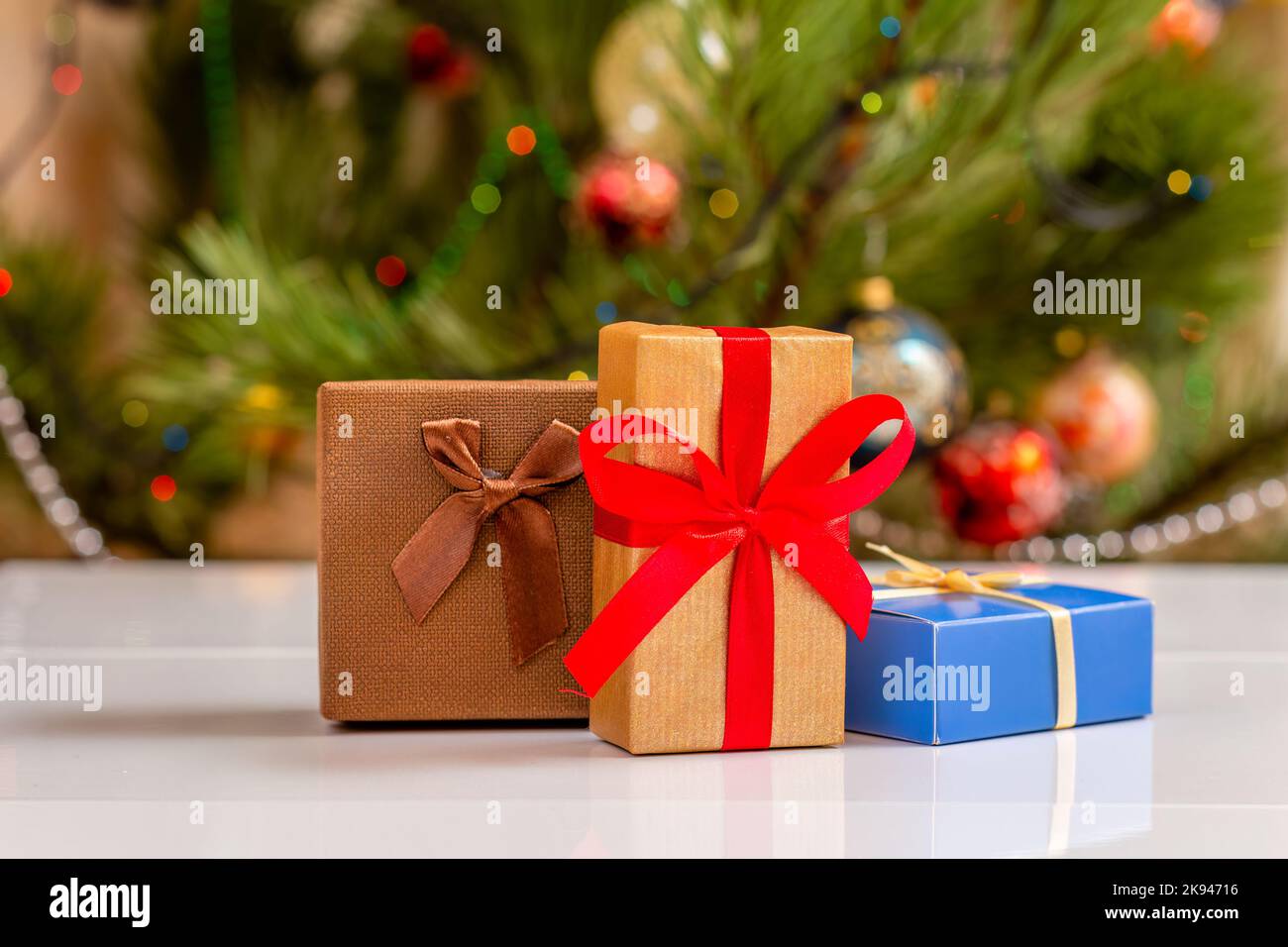 Gift boxes with bows and blurred Christmas tree with twinkling party ...