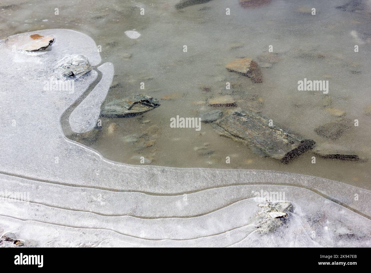 Top angle view of submerged rocks below the icy surface of a frozen ...