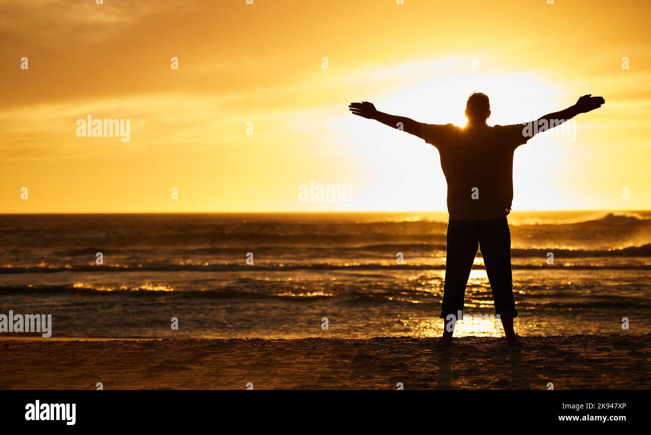 Silhouette of man with view, sunset and beach with arms out by the ...