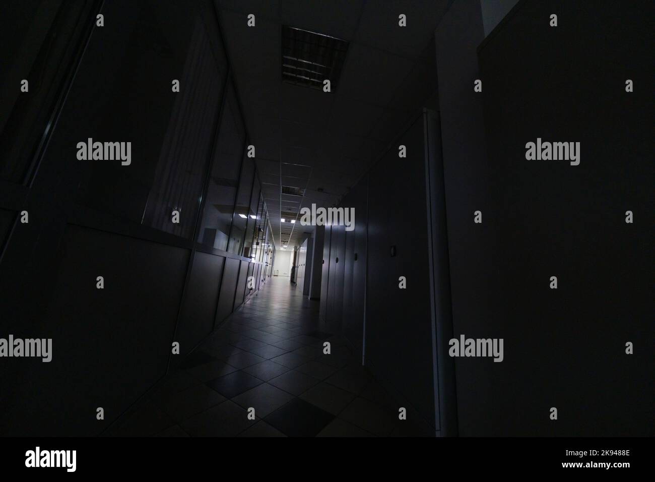 Narrow dark corridor with dim light in end inside modern building at ...