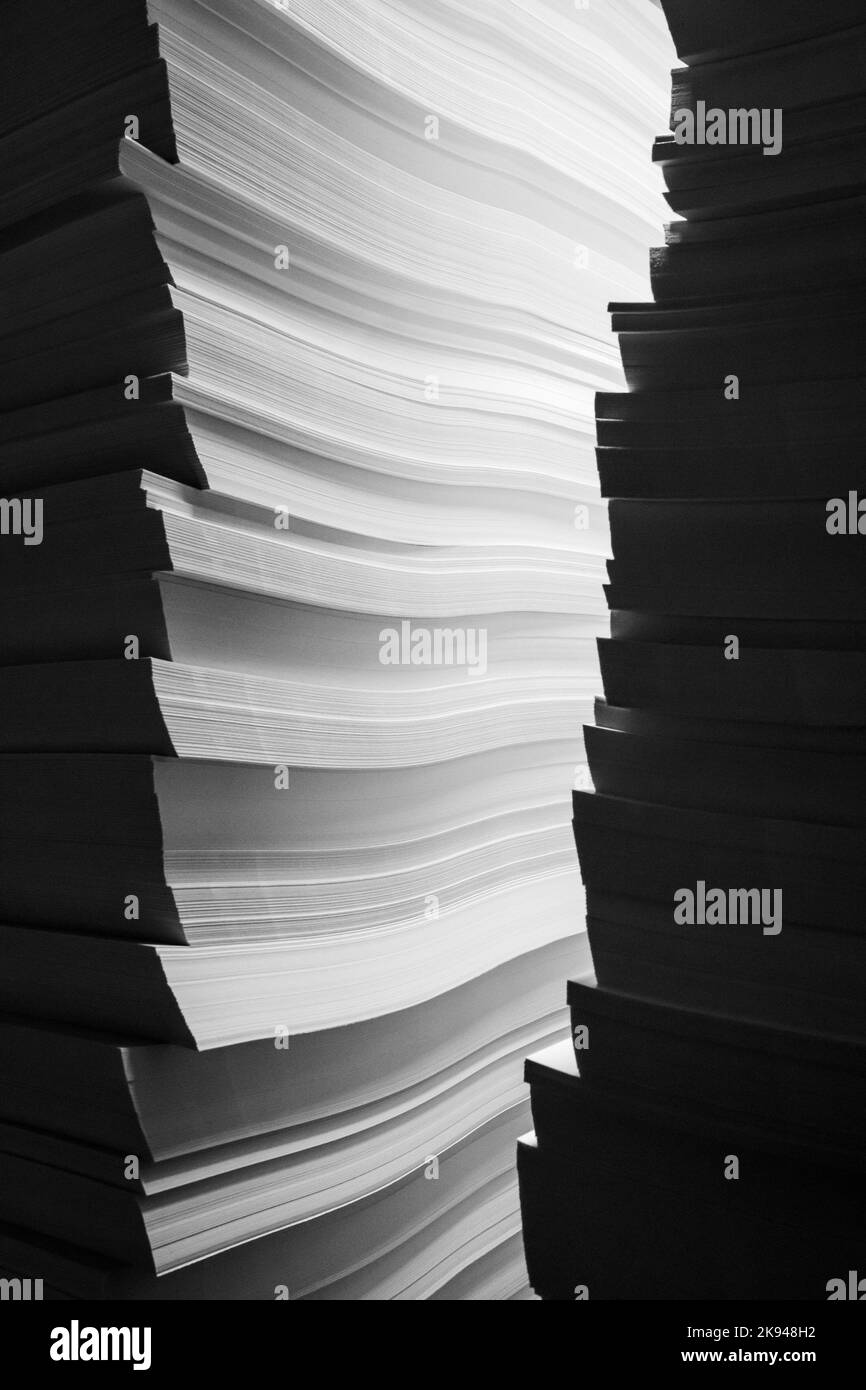 Piles of blank paper for printing illuminated with bright light in dark ...
