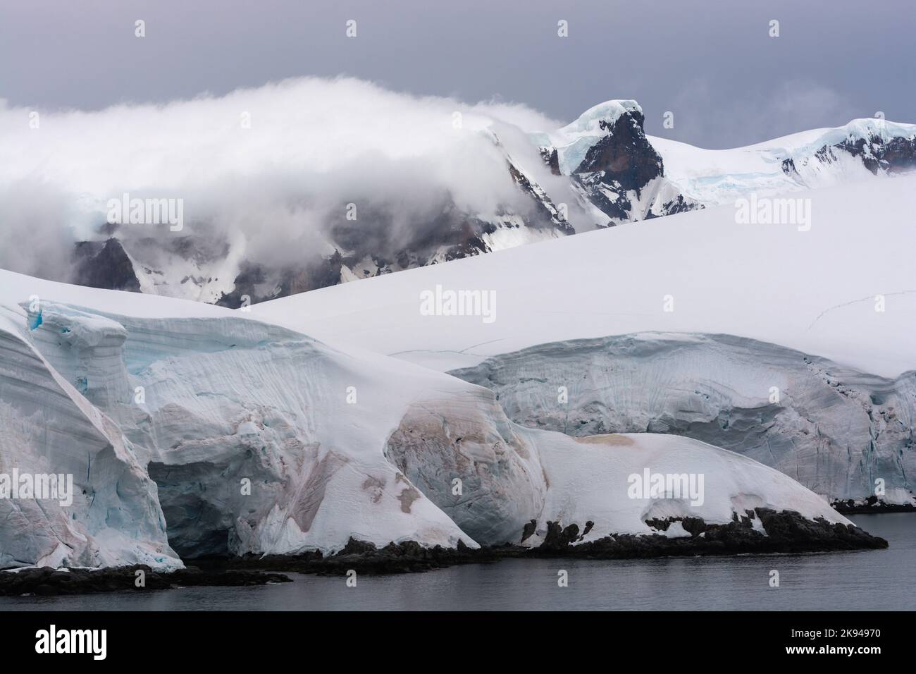 low cloud over peaks behind islands with interesting snow and ice cliff ...