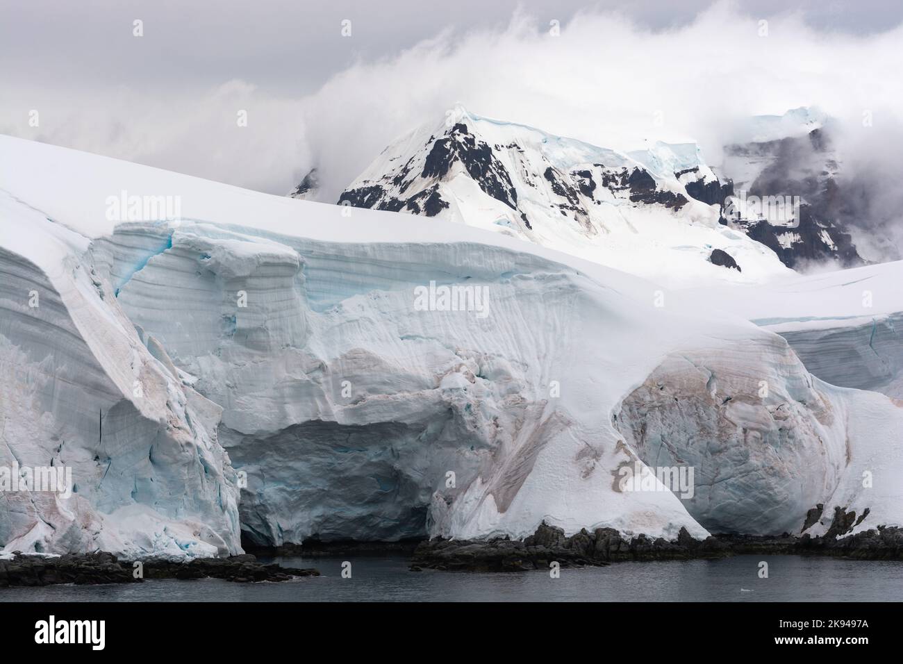 low cloud over peaks behind islands with interesting snow and ice cliff ...