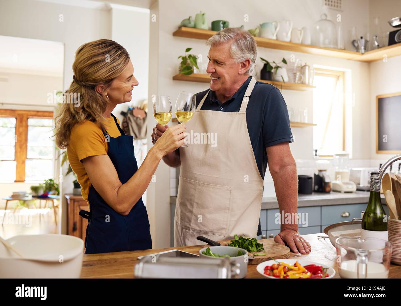 Senior, couple and wine in kitchen, toast and love while cooking, food ...