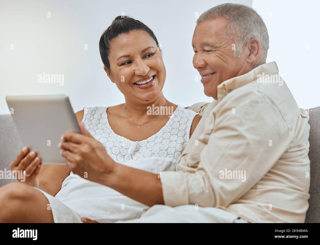 Love, senior couple and tablet being happy, smile and relax together on living room couch ...
