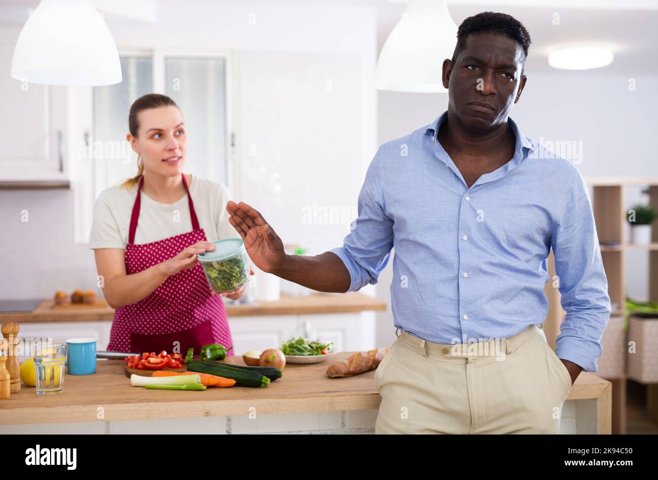 Frustrated man refusing container of vegetable salad offered by wife in ...