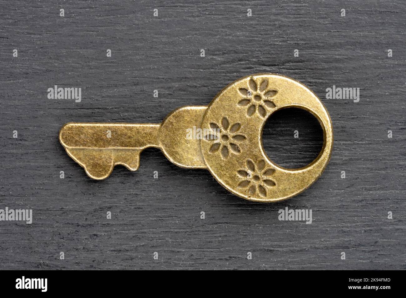 Bronze vintage antique key with flowers shape on black wooden ...
