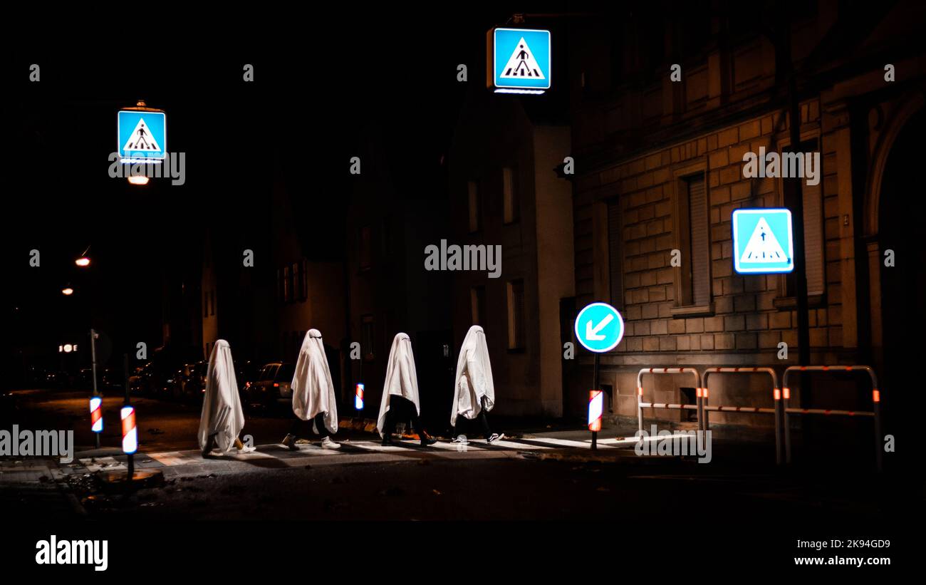 A group of people wearing ghost costumes and crossing the street in a ...