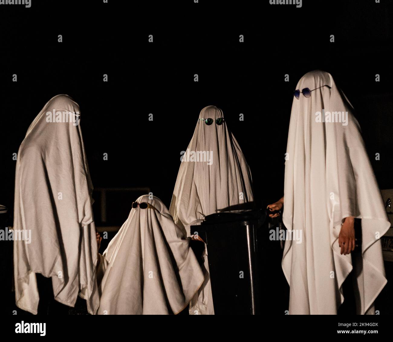 A group of people wearing ghost costumes against dark background Stock ...
