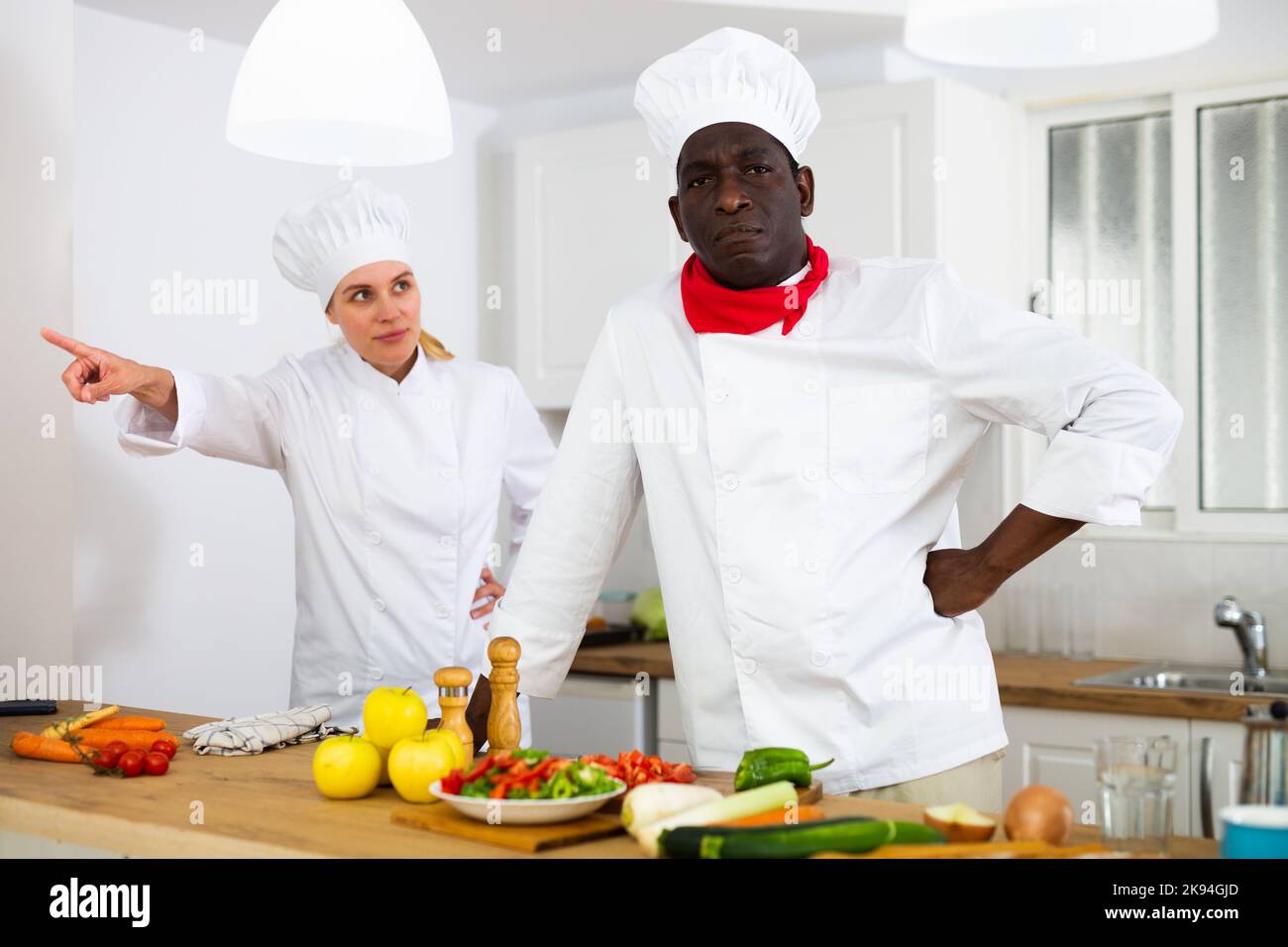 Strict female chef reprimanding male colleague in private kitchen Stock ...