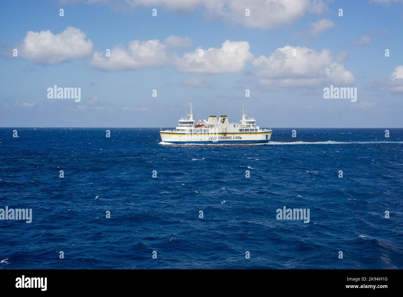 A ferry moving through the sea with a cloudy sky in the background ...