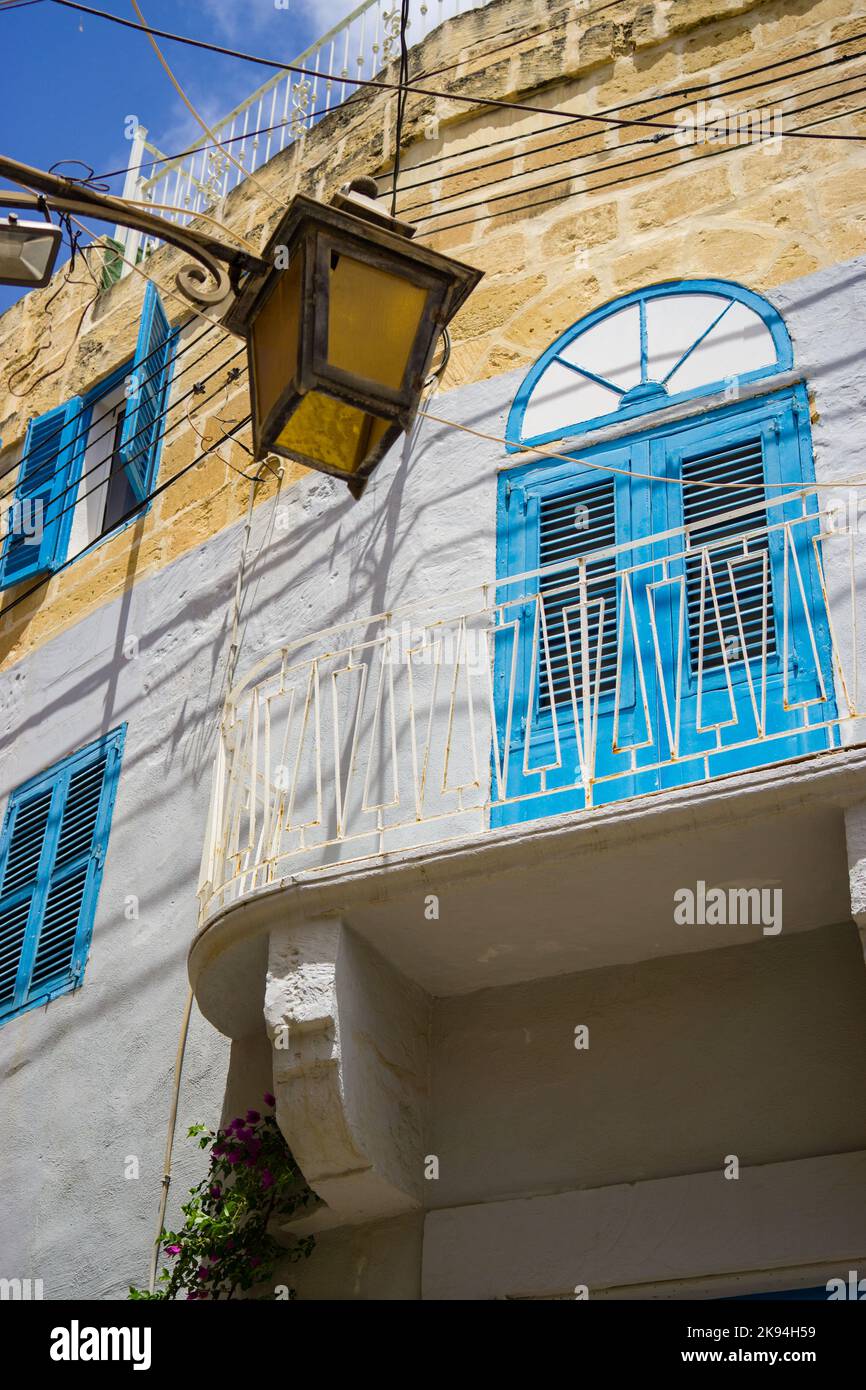 A vertical shot of a balcony with blue window shutters on a brick wall ...