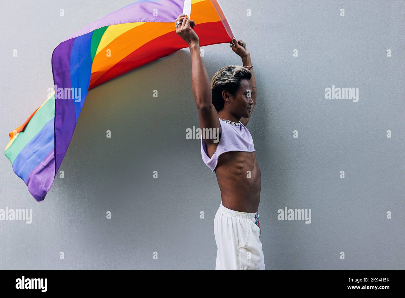 Stylish guy holding rainbow LGBT flag above his head Stock Photo - Alamy