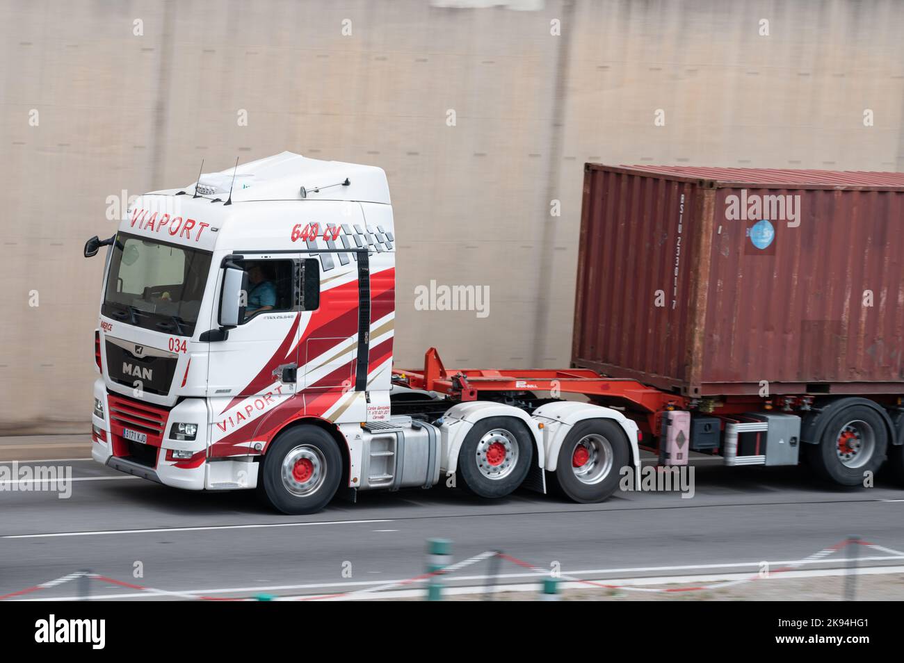 A White MAN TGX truck with red drawings loading a red container trailer ...