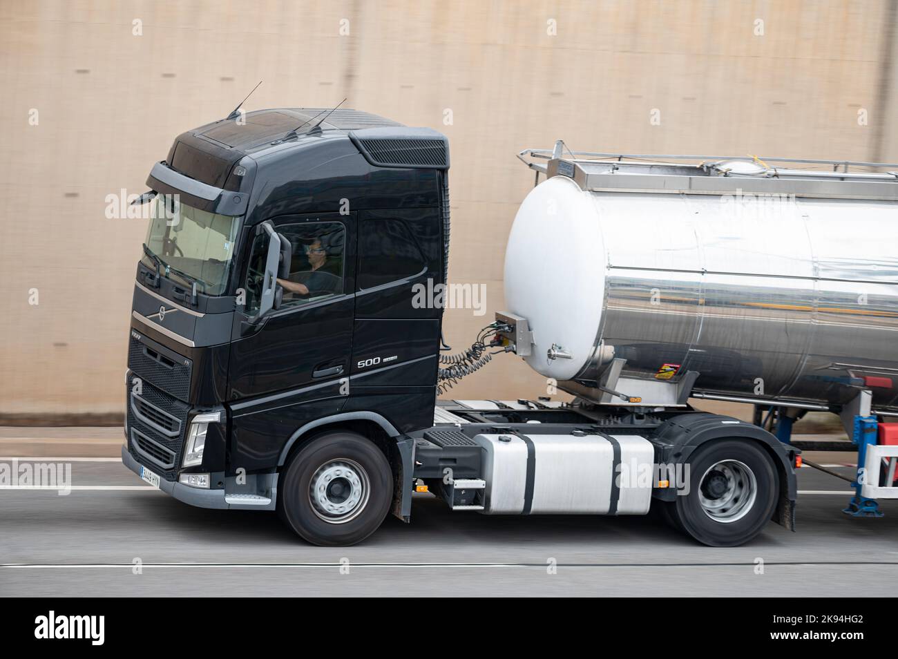 A black Volvo FH truck loading a white container trailer along ...