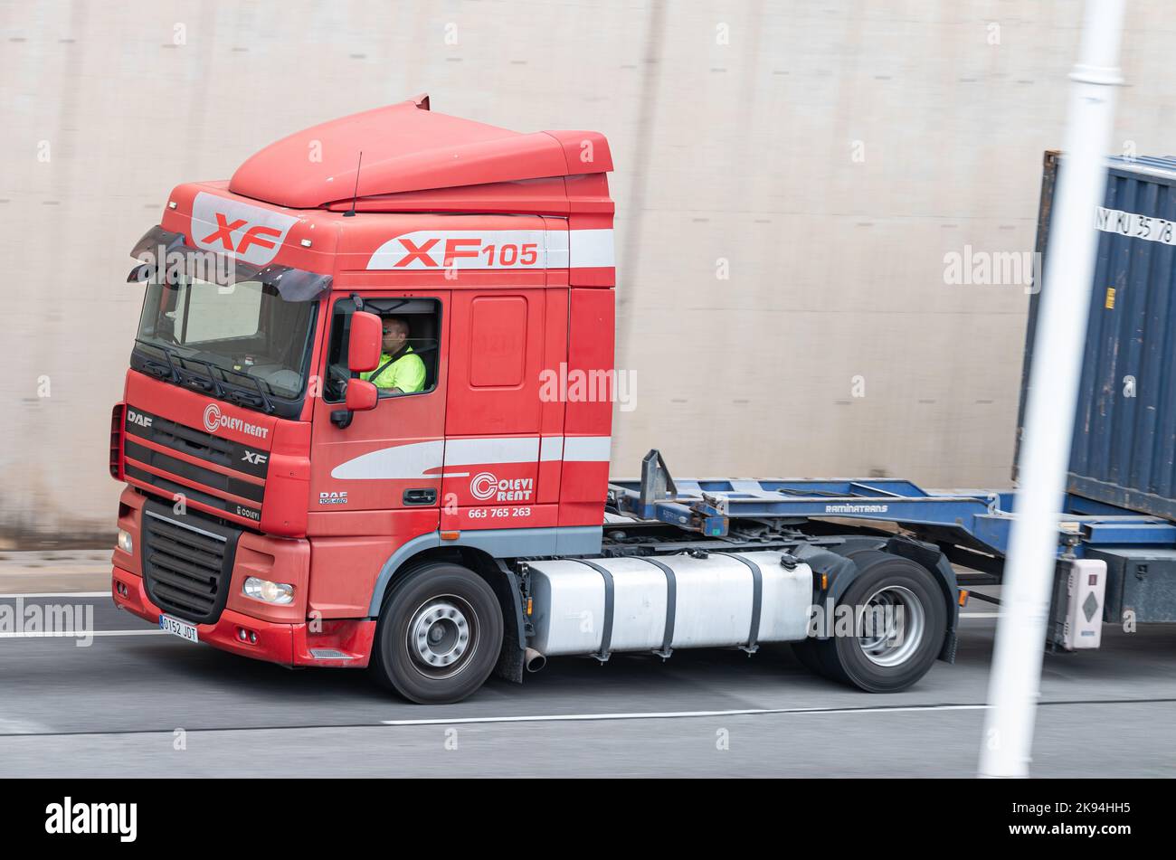 A closeup of a Red DAF XF truck loading a container trailer along ...