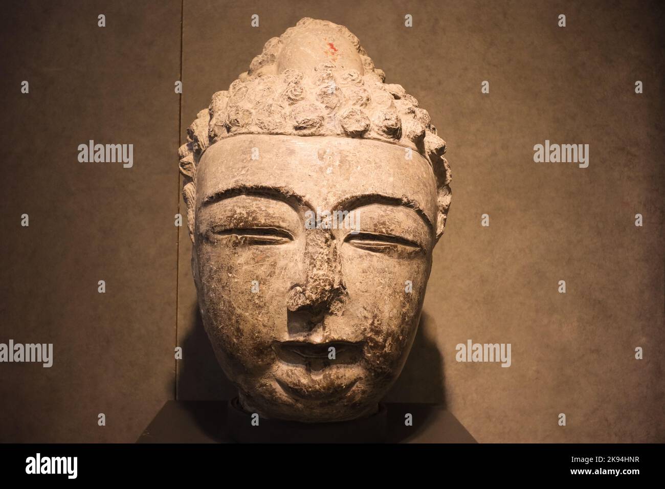 A closeup of a carved stone artwork of Buddha's face in the exhibition ...