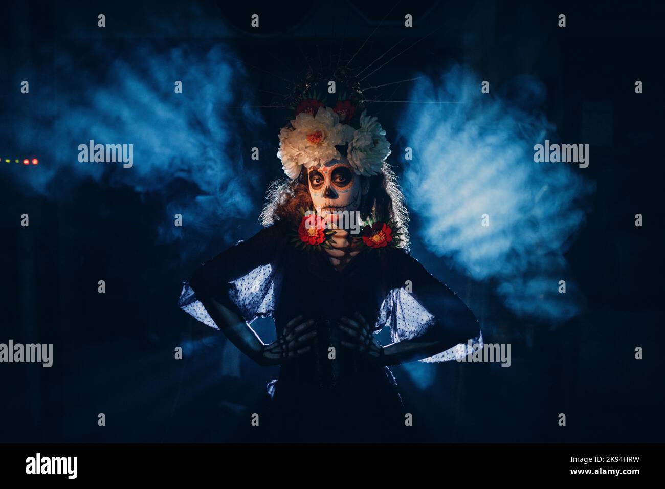Woman with mexican skull halloween makeup in dark with backlight rays ...