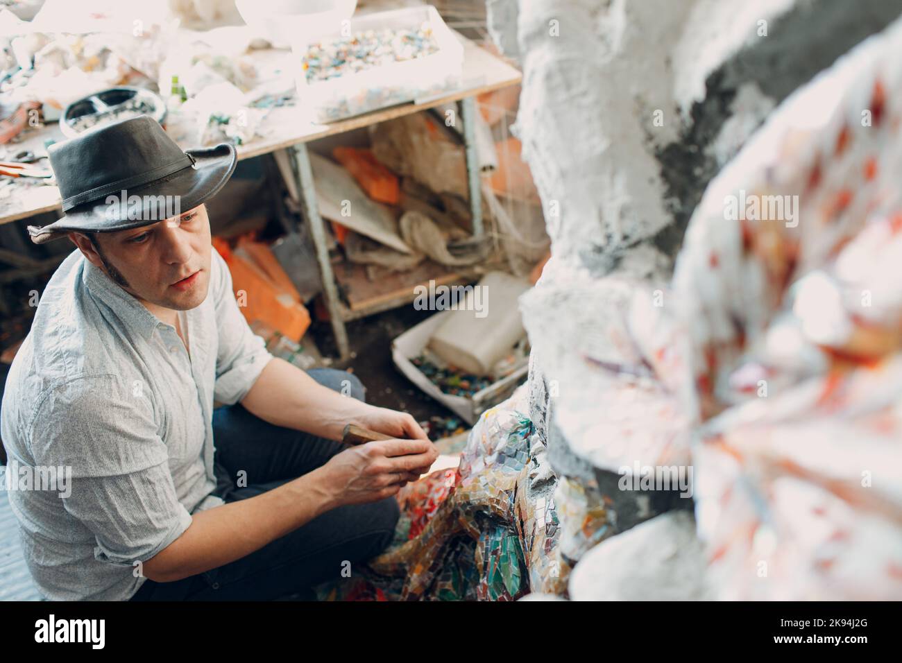 Man mosaics master in hat making smalt glass mosaic panel. Male ...