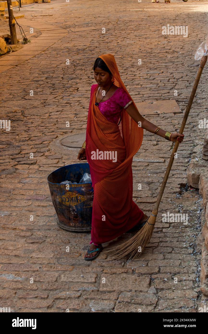 A vertical shot of a woman sweeping the streets of Golden Fort with a ...